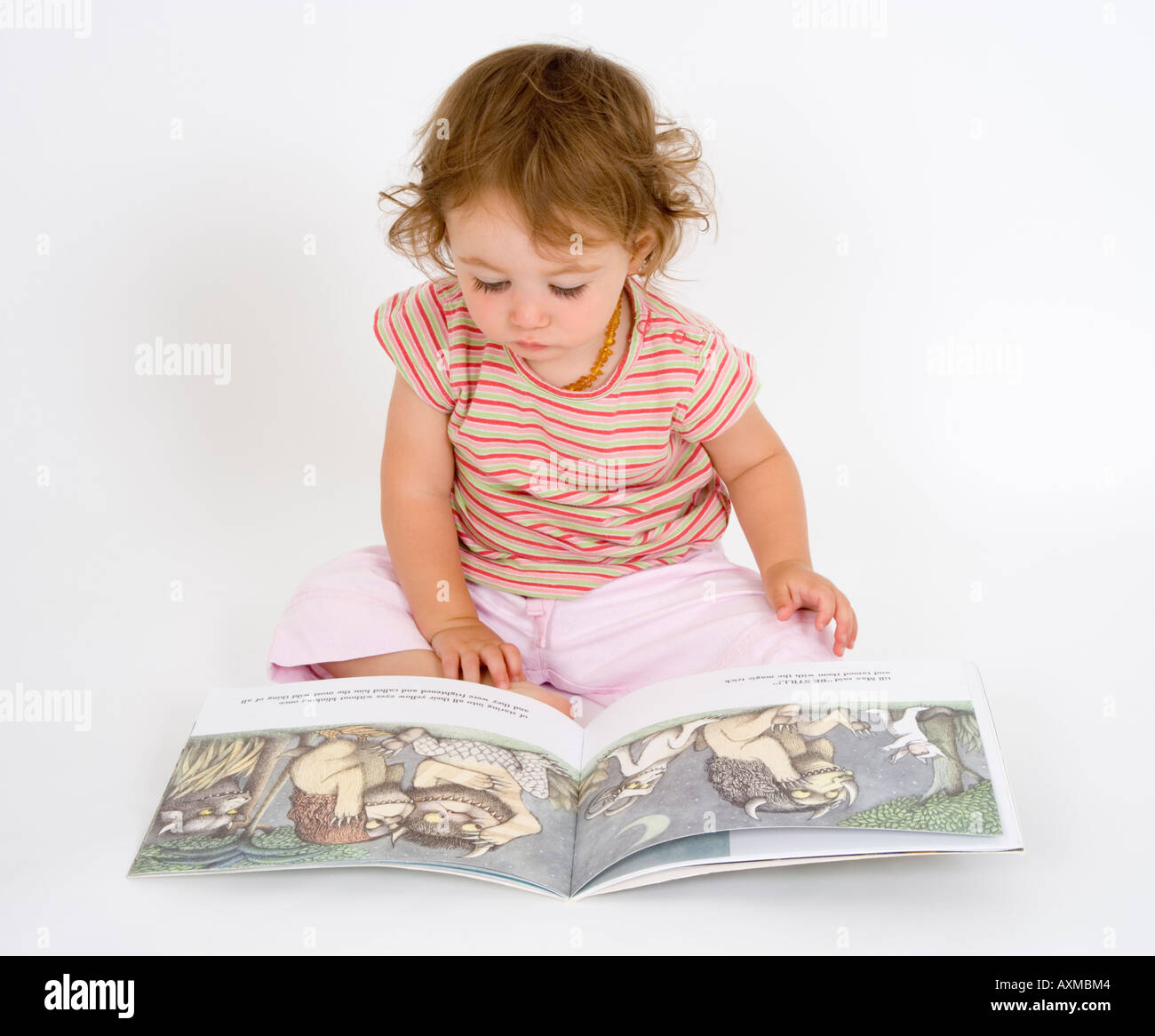 Toddler sat on floor looking at book Stock Photo - Alamy