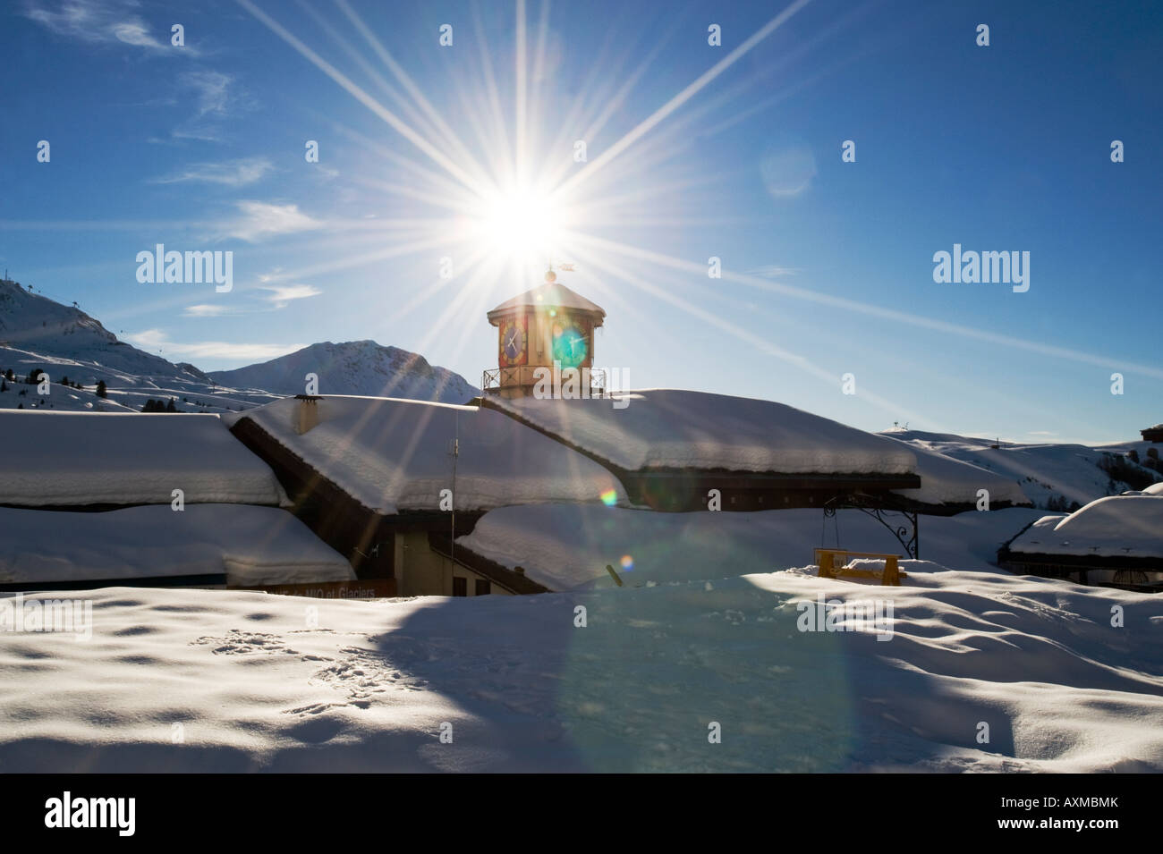 snow covered rooftops of french alpine village with clock tower and ...