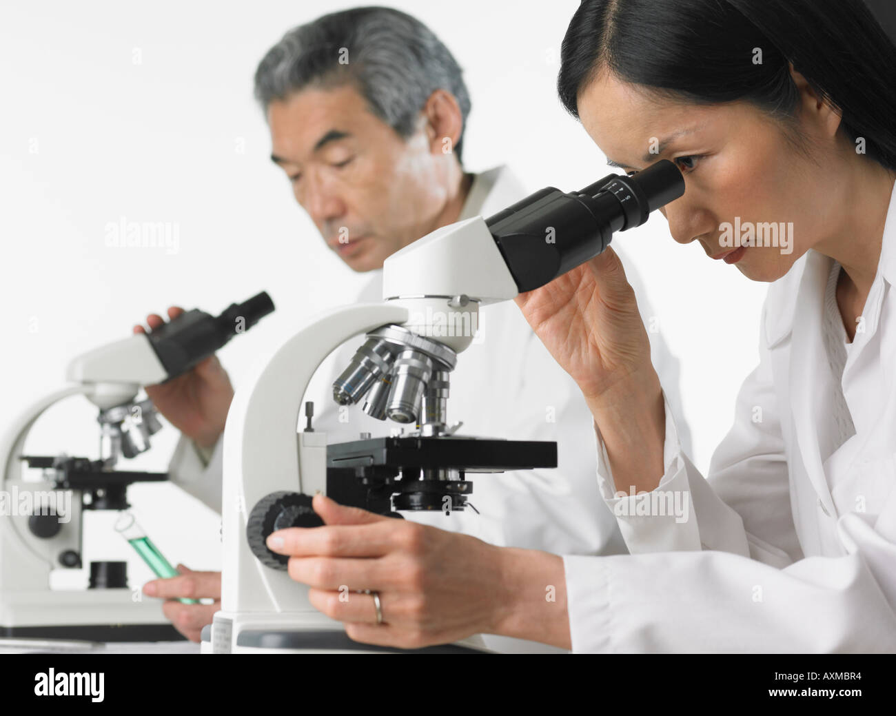 Man and woman in lab coats using microscopes Stock Photo - Alamy