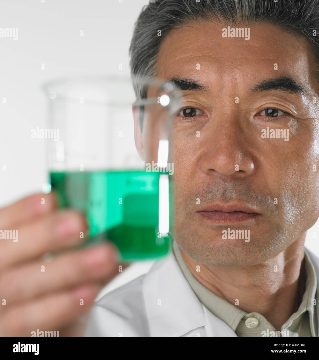 Man looking at beaker of fluid Stock Photo - Alamy