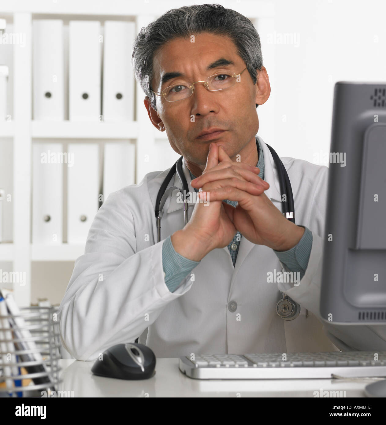 Senior male doctor sitting at computer Stock Photo - Alamy