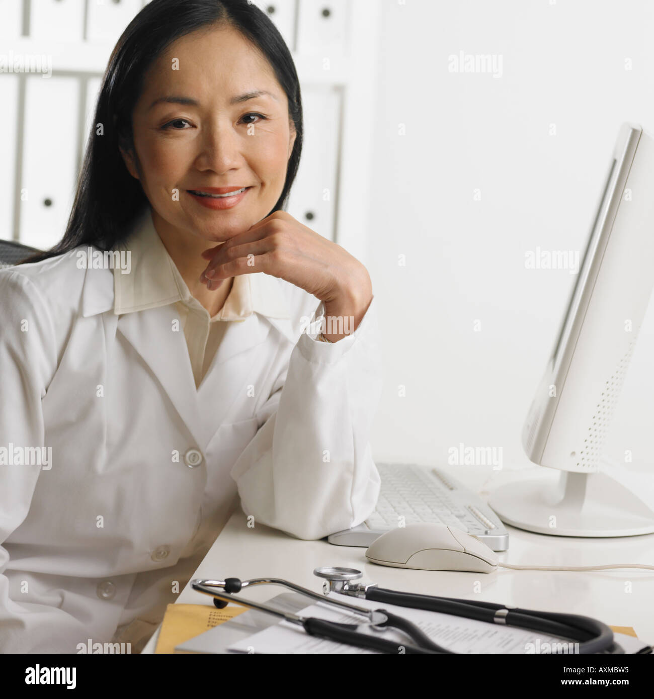 Female doctor sitting at computer smiling Stock Photo - Alamy