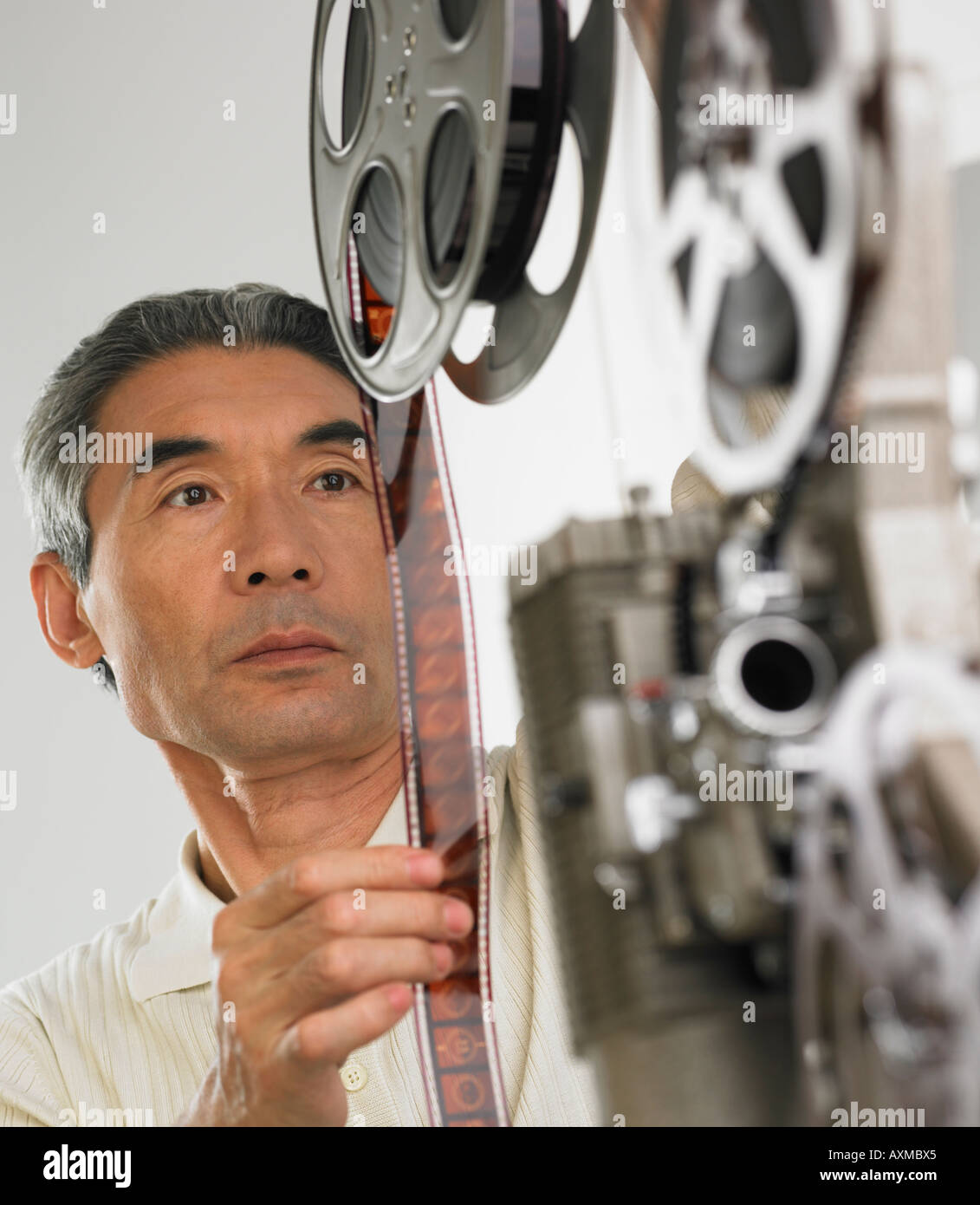 Asian man looking film in projector Stock Photo - Alamy