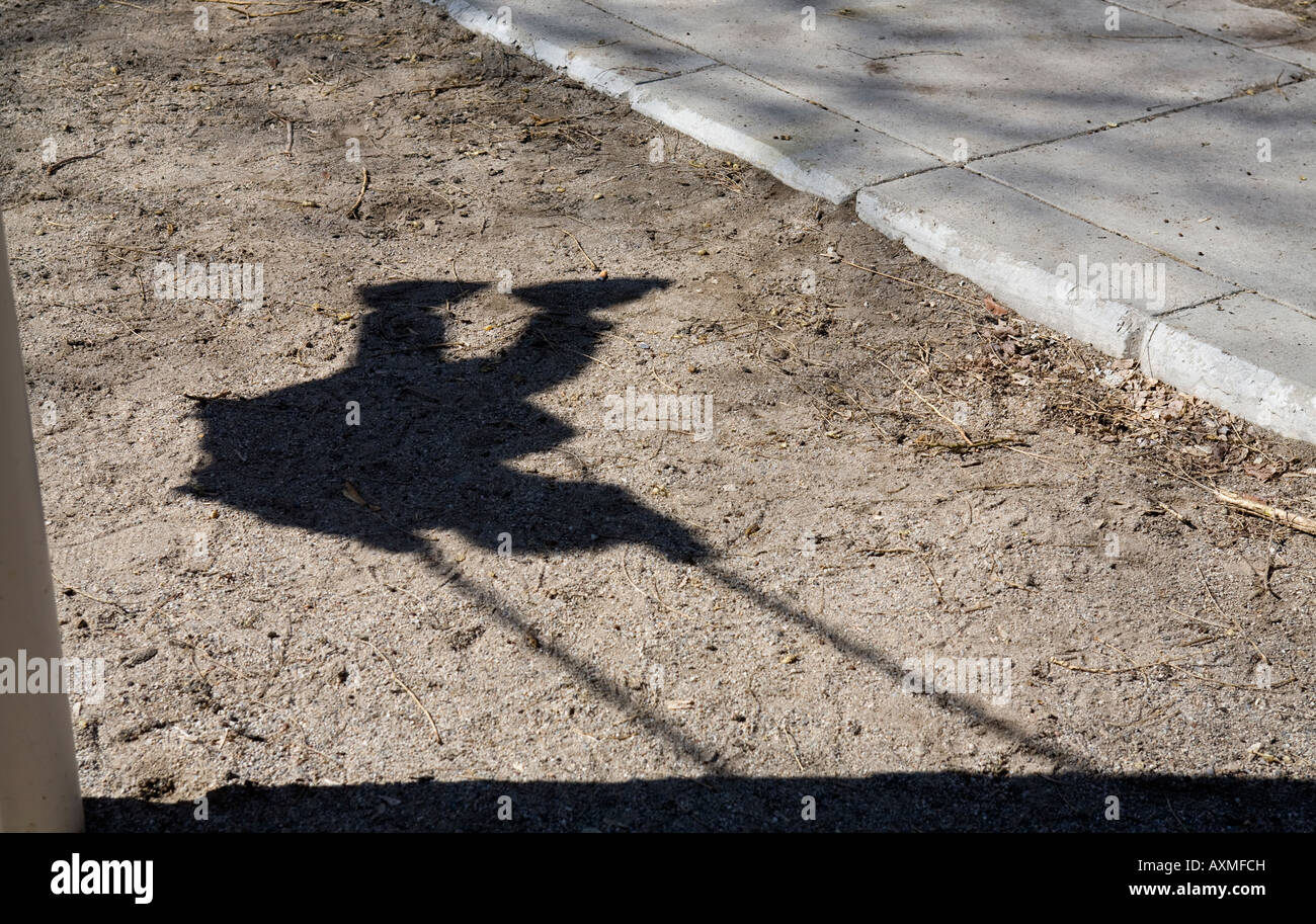 The shadow of a boy being pushed on a swing by his dad at the park ...
