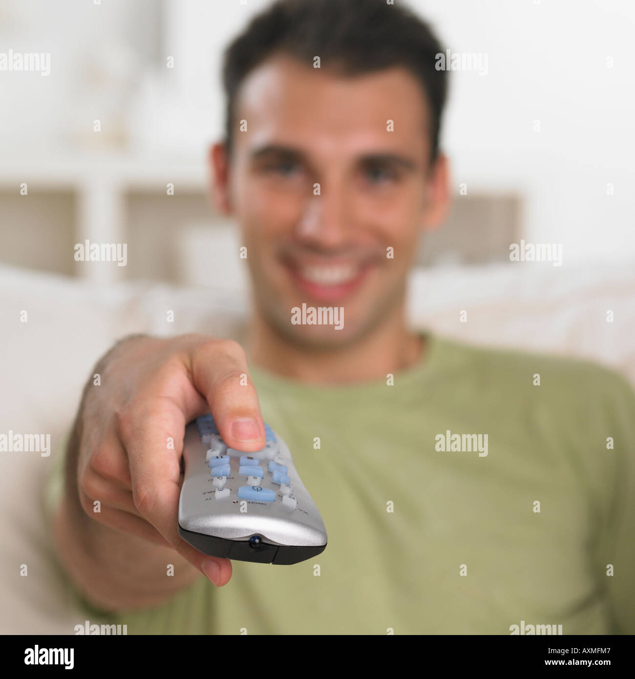 Man sitting on sofa pointing remote control Stock Photo - Alamy