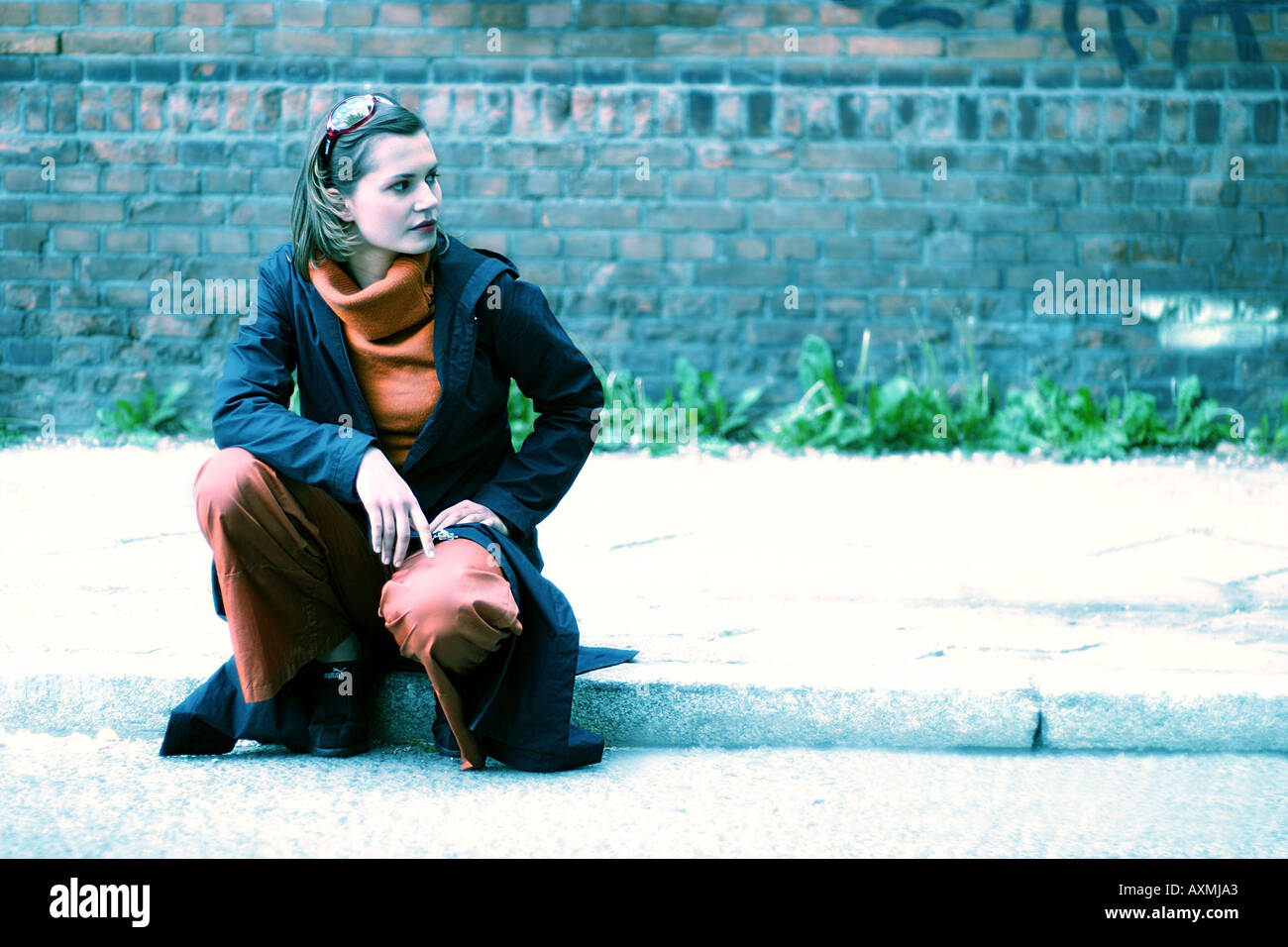 Young woman sitting on curb hi-res stock photography and images - Alamy