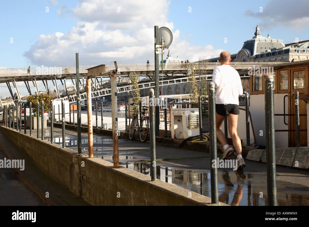 Man Jogging along the banks of the River Seine with Solferino Bridge ...