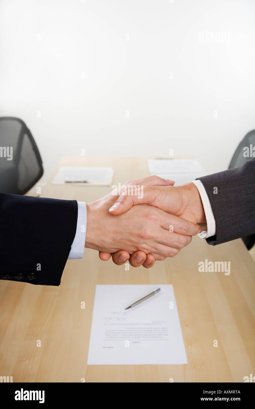 Businessmen shaking hands over table Stock Photo - Alamy
