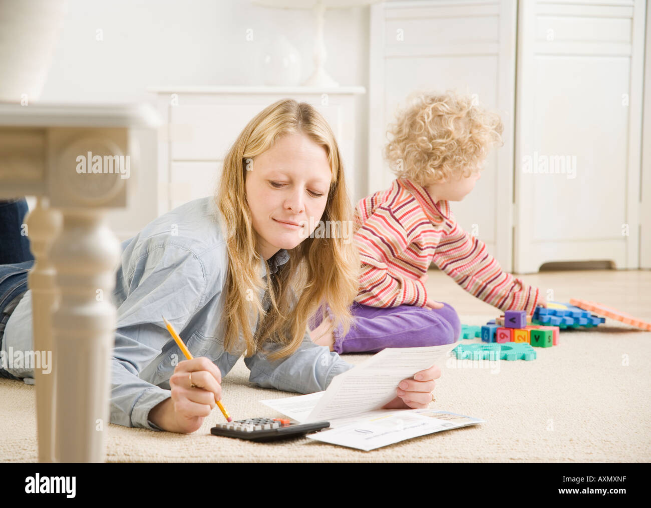 Mother working on calculator while child plays Stock Photo - Alamy