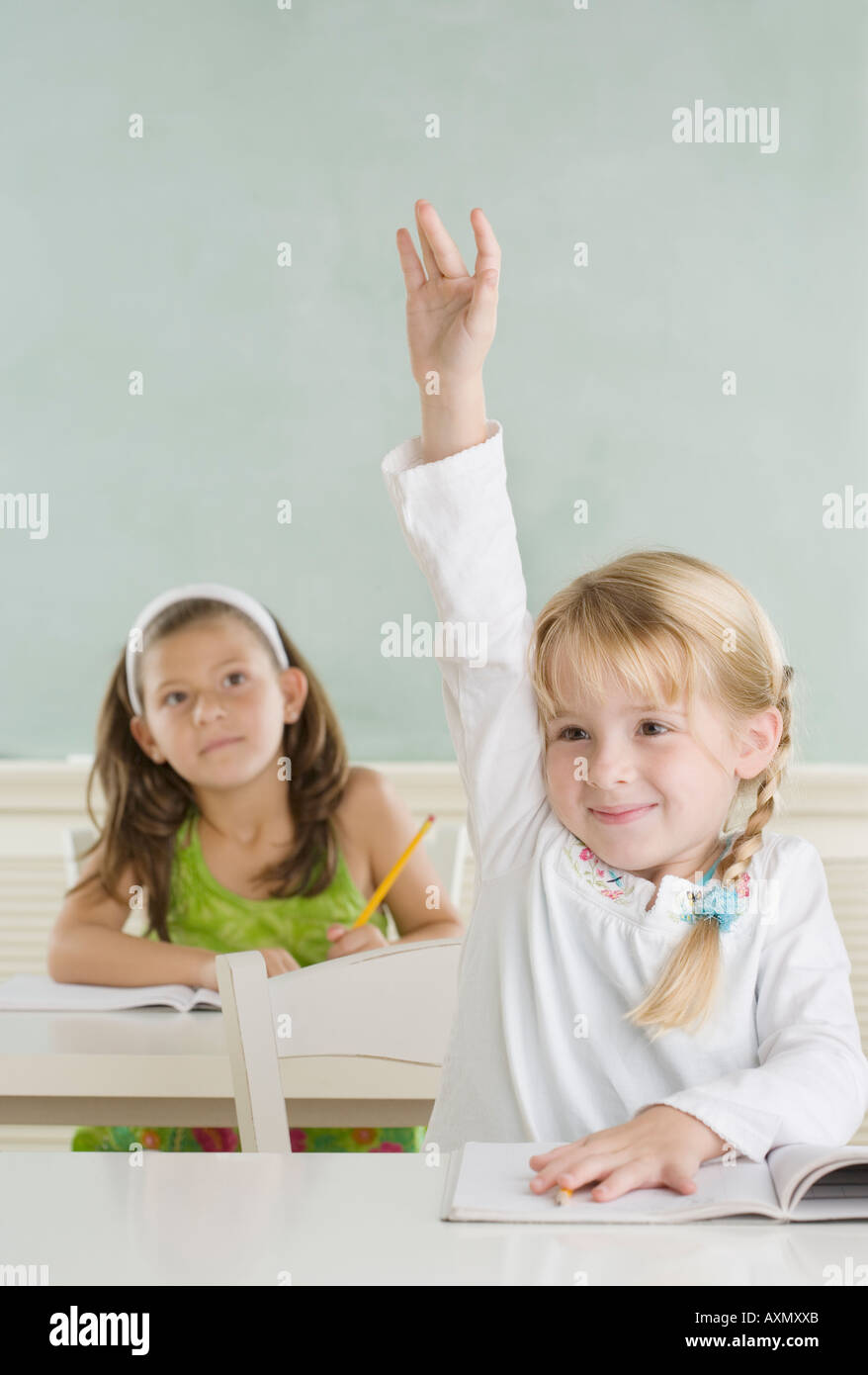 Young girl raising hand in class Stock Photo - Alamy