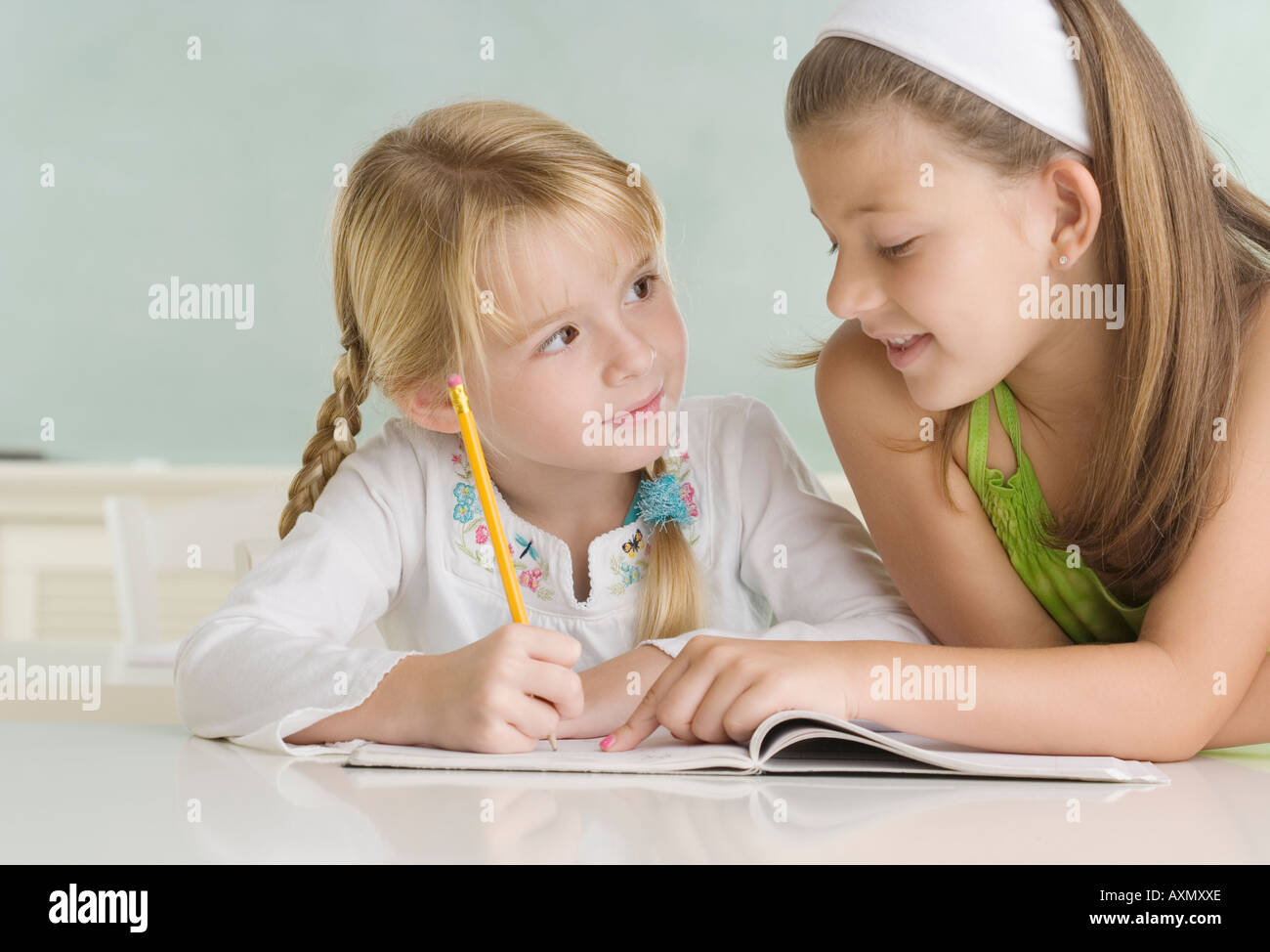 Girl helping classmate at desk Stock Photo - Alamy