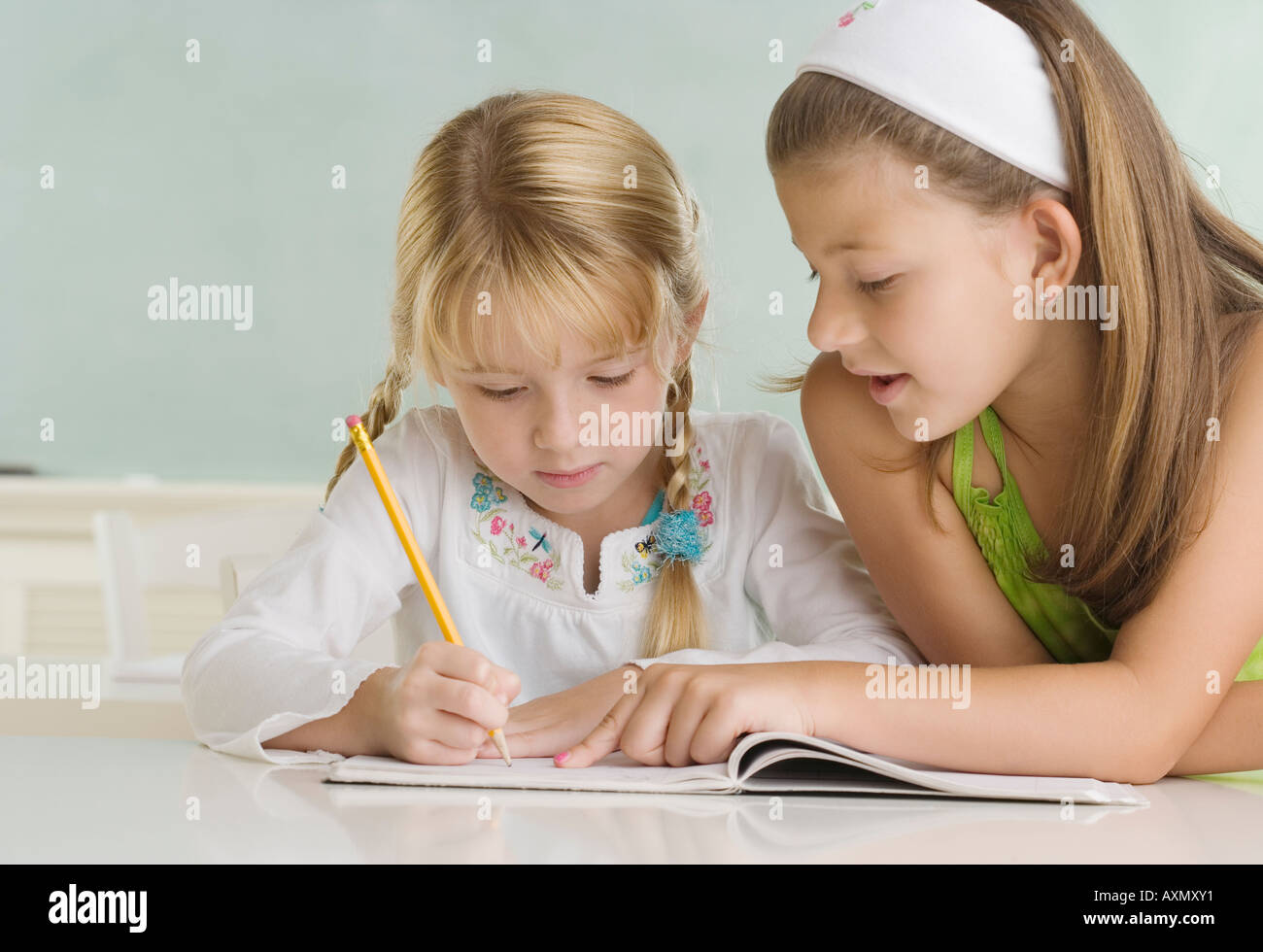 Girl helping classmate at desk Stock Photo - Alamy