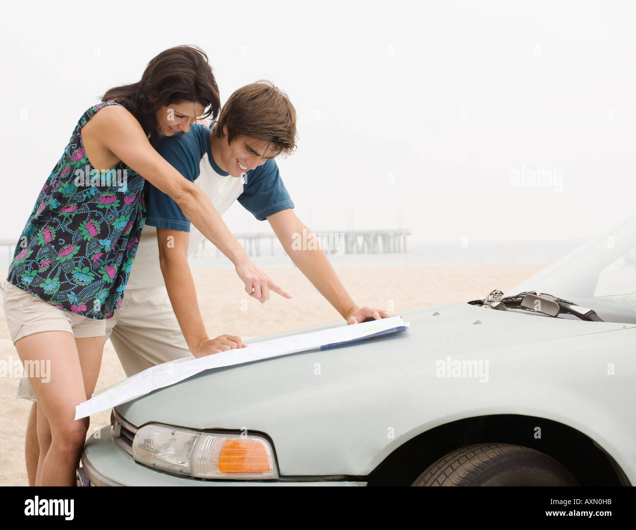 Couple looking at map on car hood at beach Stock Photo - Alamy