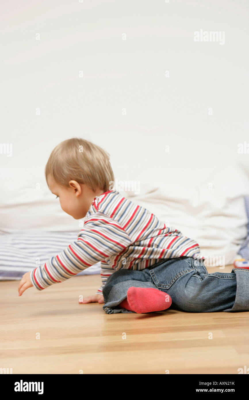 Baby boy sitting on a floor, trying to turn around Stock Photo - Alamy