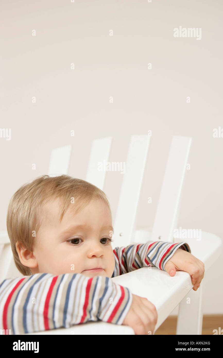 Baby boy sitting on a white chair Stock Photo - Alamy