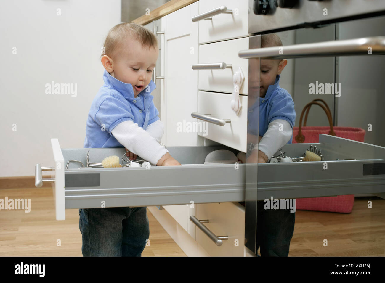 Baby boy emptying a kitchen drawer Stock Photo - Alamy