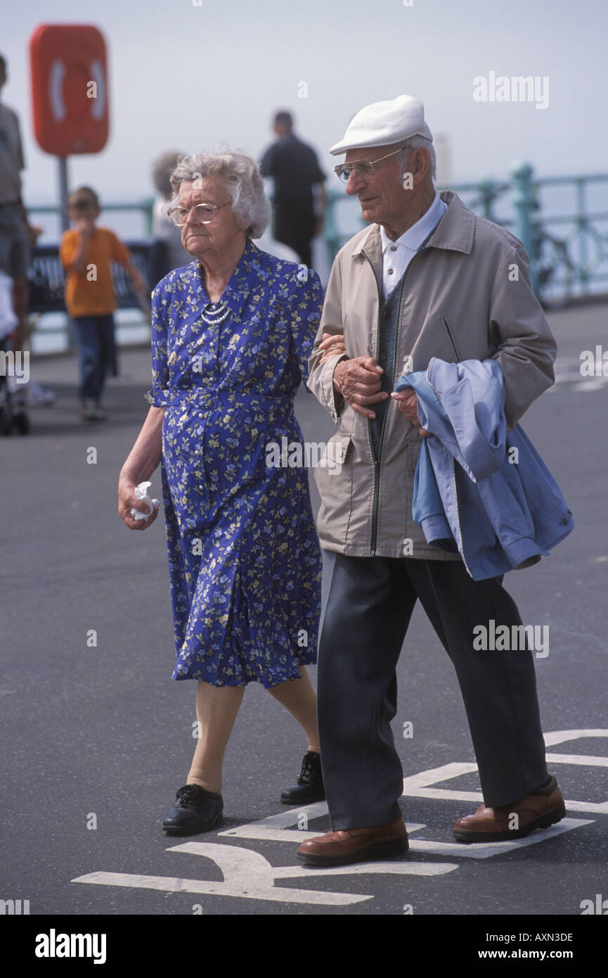 Seniors old age pensioners walking on the promenade. A couple, husband ...