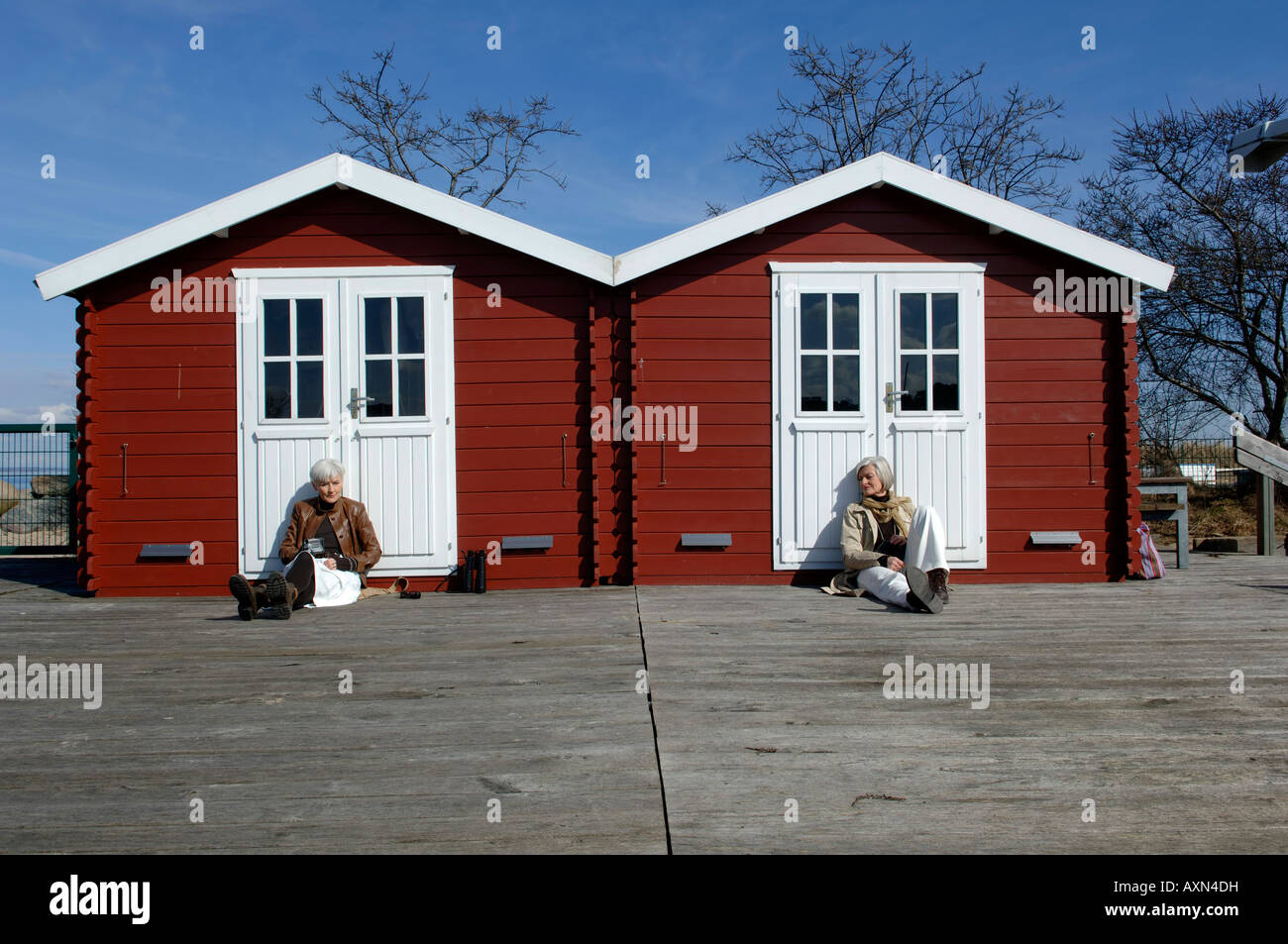 Two mature women sitting in front of huts Stock Photo - Alamy