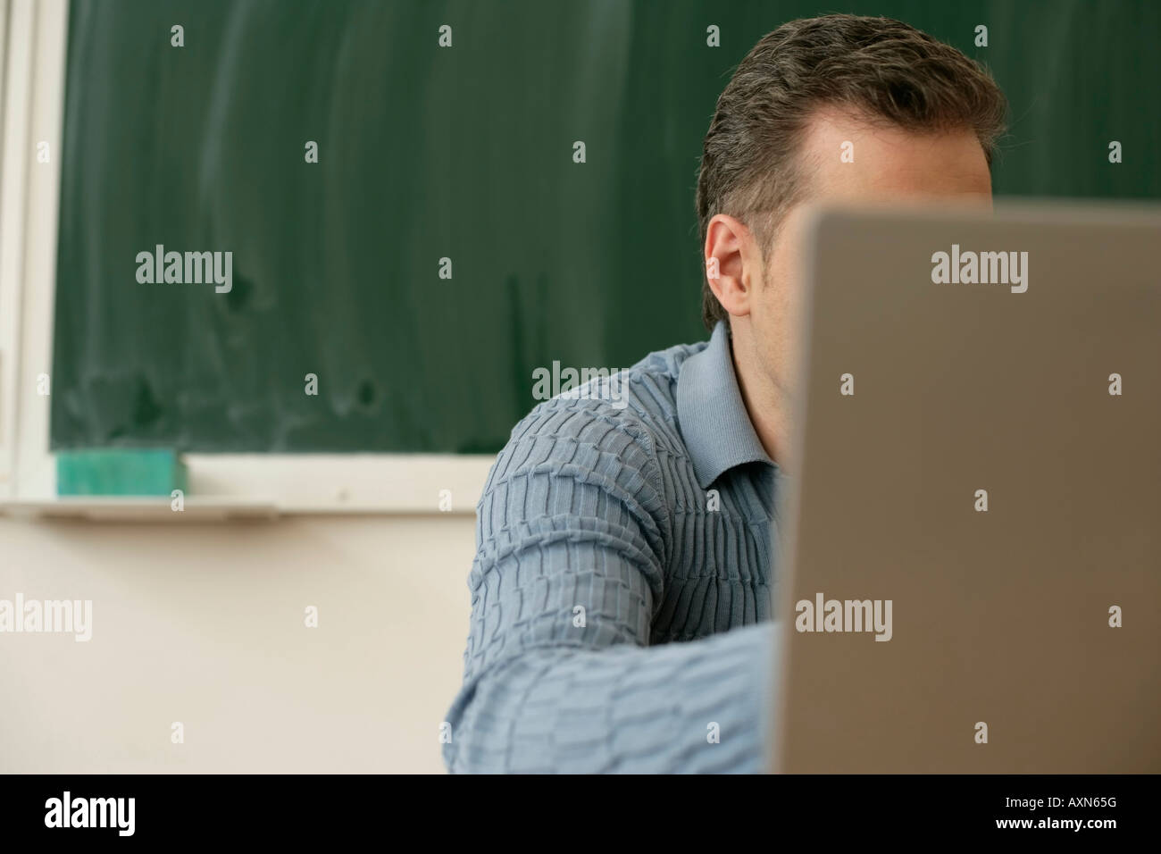 Teacher sitting behind a laptop Stock Photo - Alamy