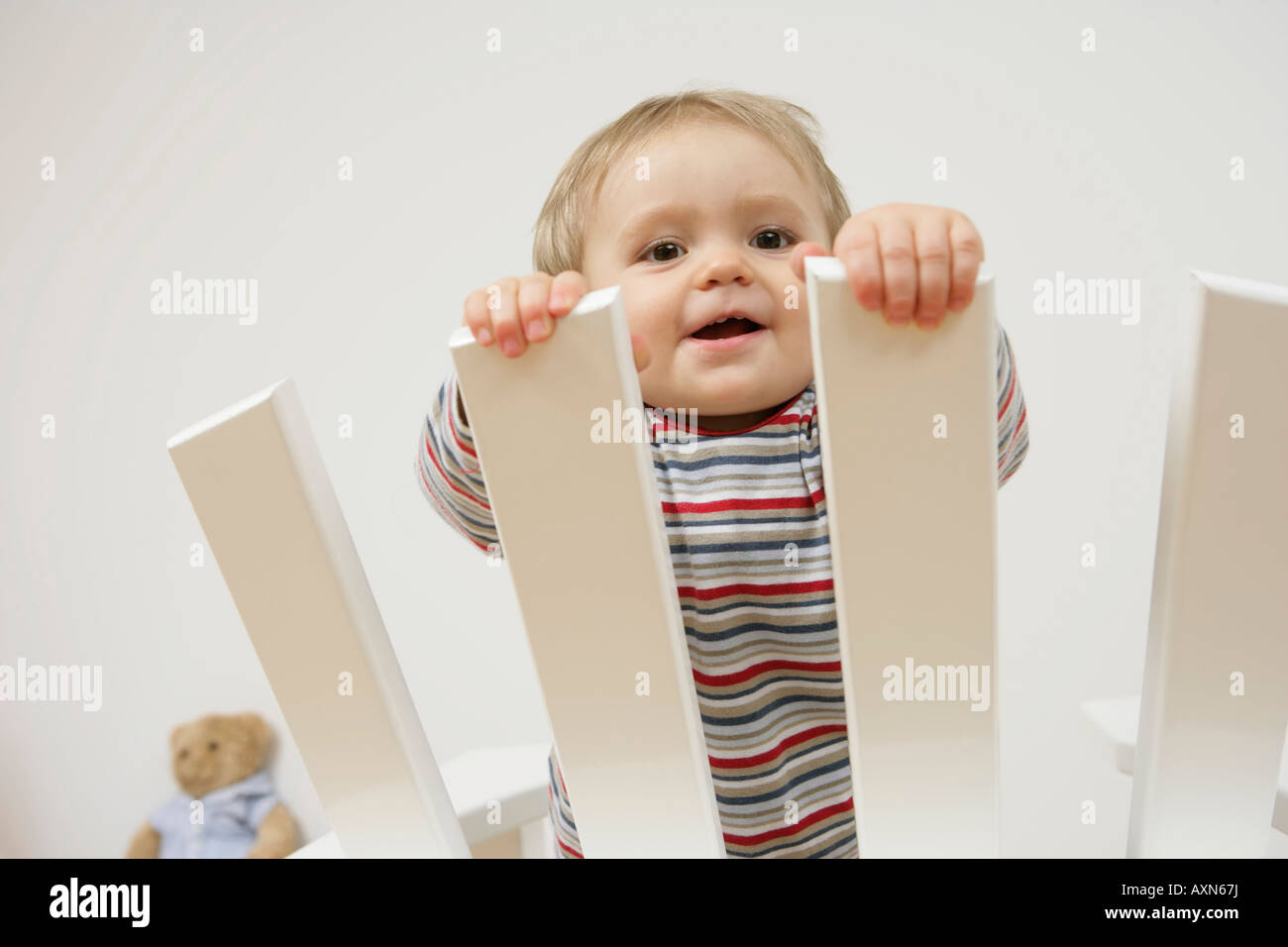Baby boy lifting himself at a back of a chair Stock Photo - Alamy