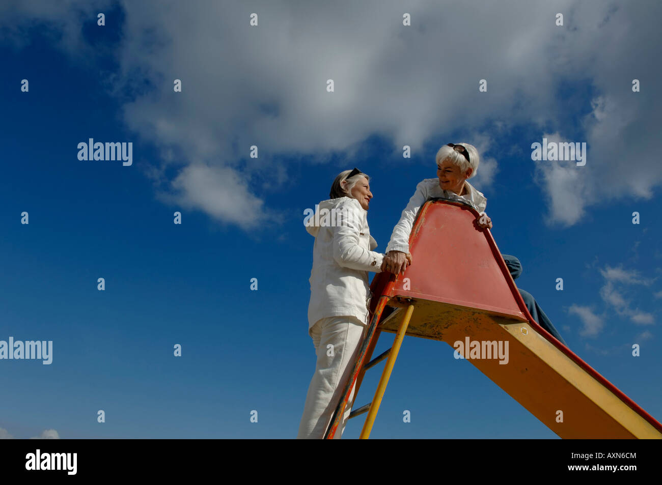 Two mature women at a slide Stock Photo - Alamy