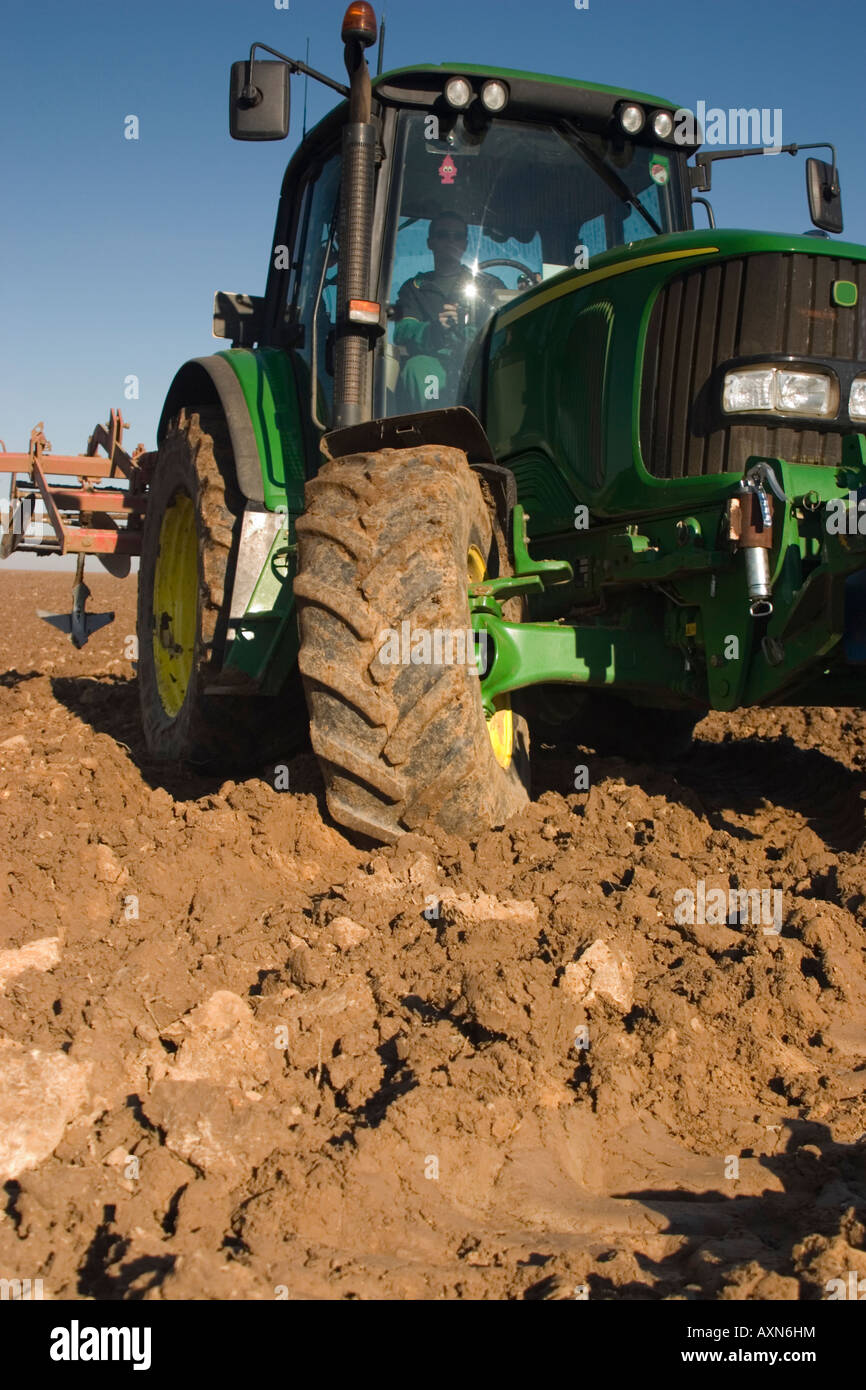 Tractor mounted with a cultivator turning at the end of a field close ...