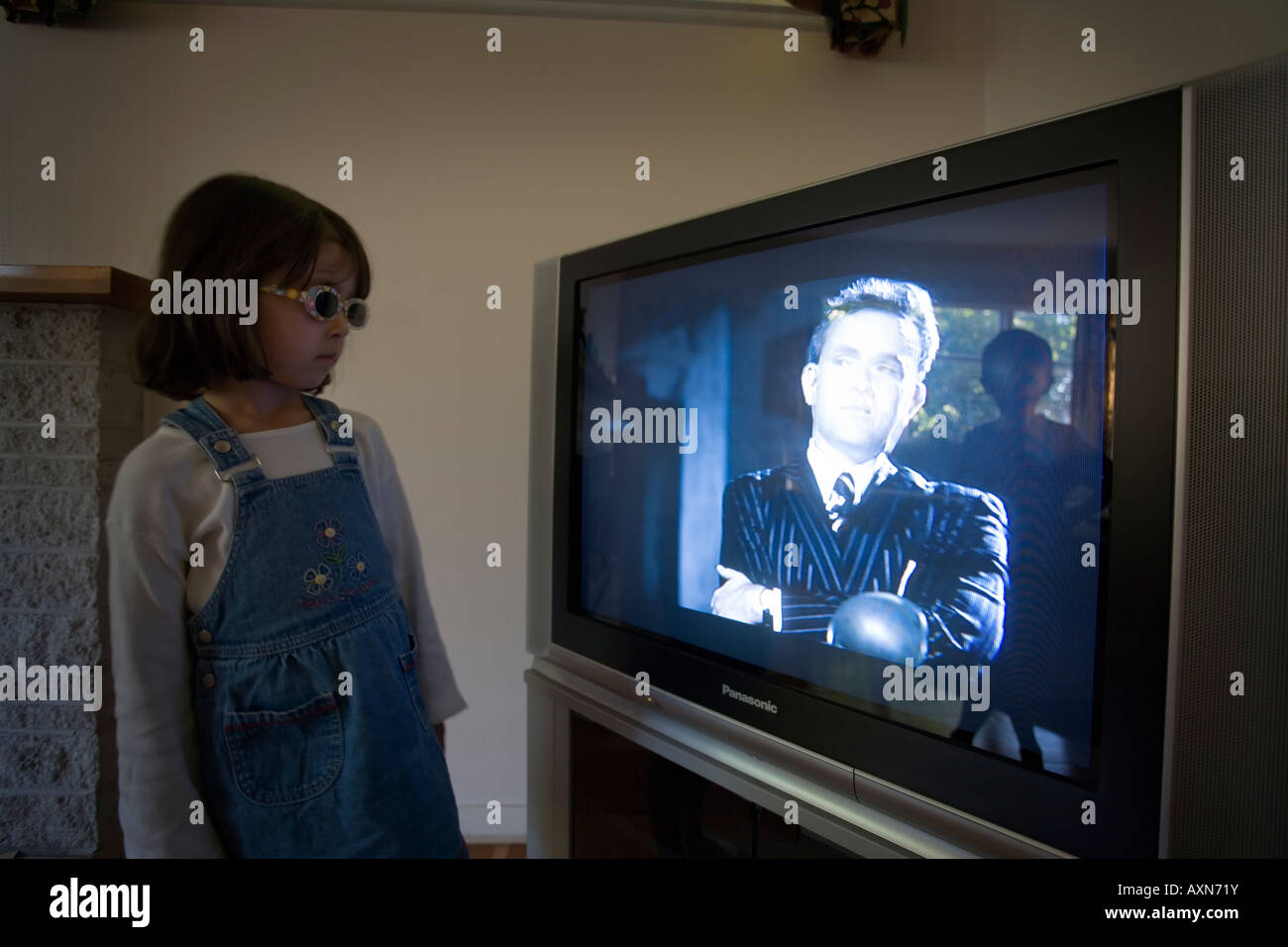 Girl aged four with sunglasses watches TV with man on programme and ...