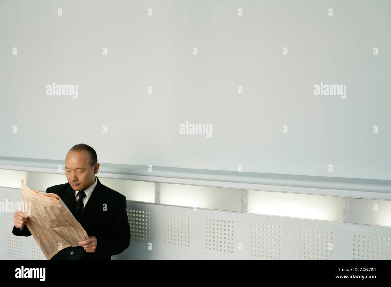 Asian businessman reading a newspaper Stock Photo - Alamy