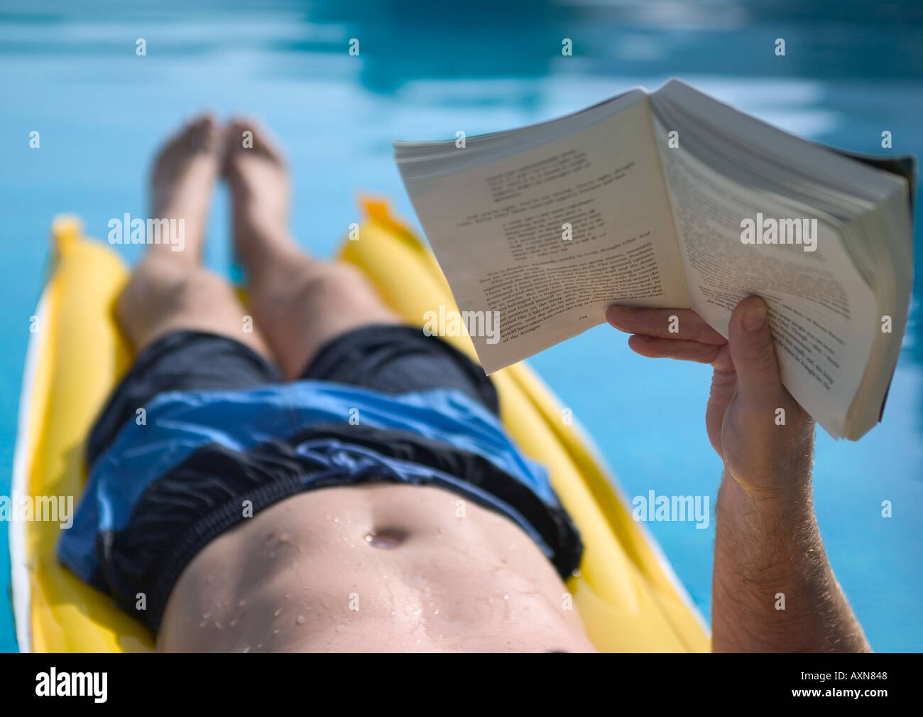 man reading book while lying on inflatable bed in swimming pool Stock ...
