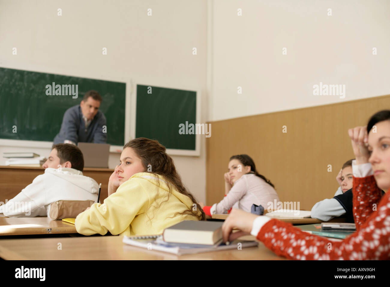 Bored pupils looking out of a window, teacher in front of a blackboard ...