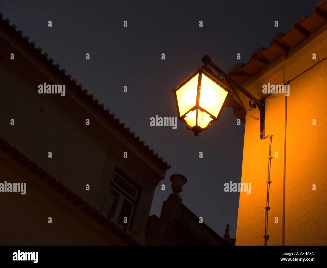Ornate streetlamp illuminated at night on gable wall Stock Photo - Alamy