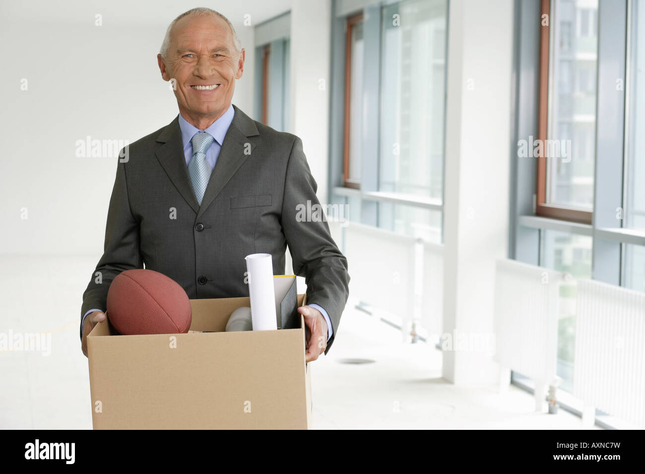 Smiling manager carrying cardboard box with soccer ball Stock Photo - Alamy