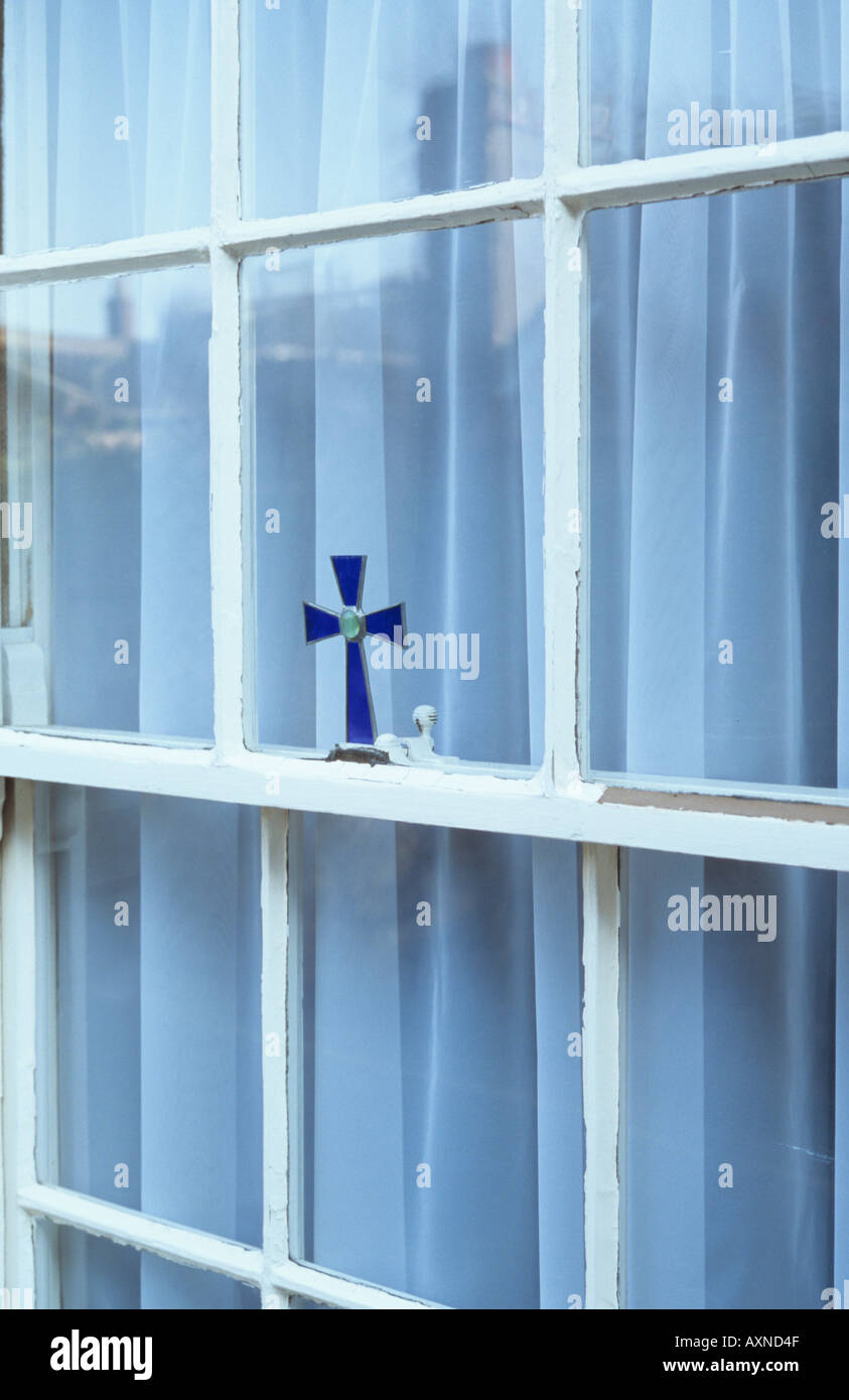 Small blue crucifix set with green stone standing in a domestic sash ...