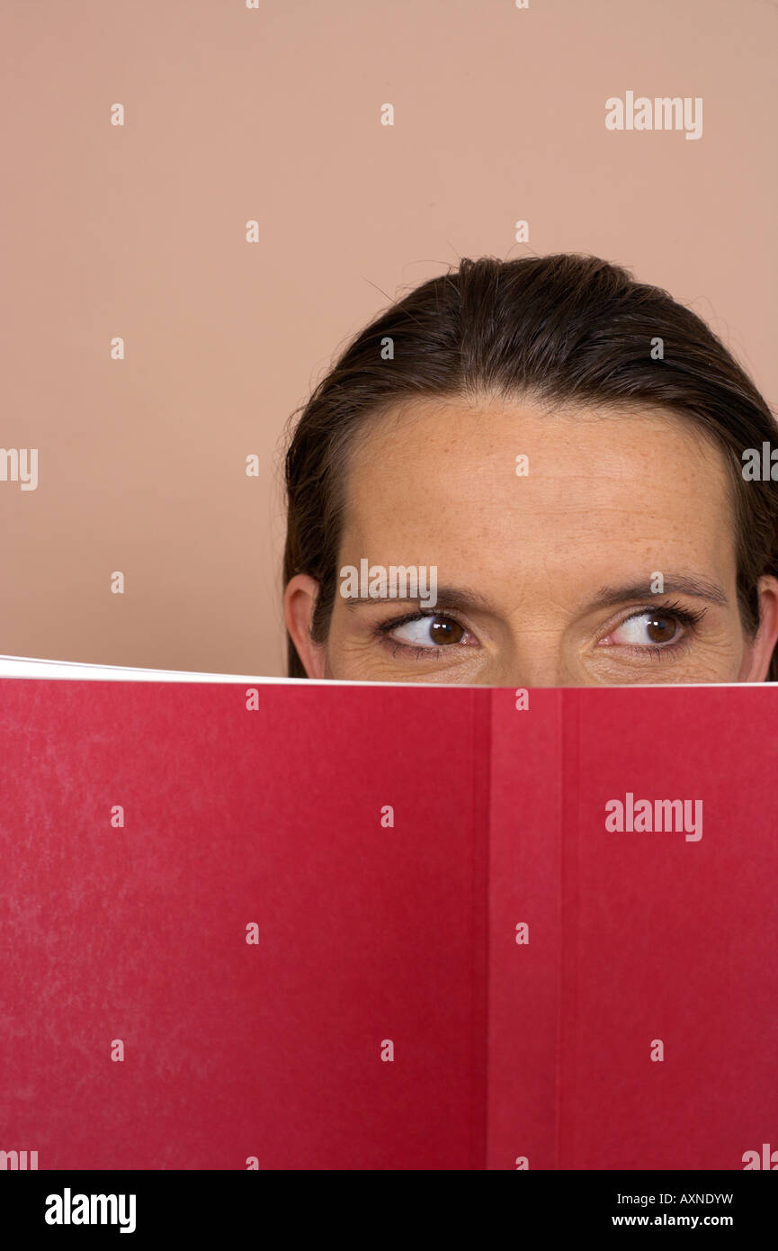 Woman looking over a red book Stock Photo - Alamy
