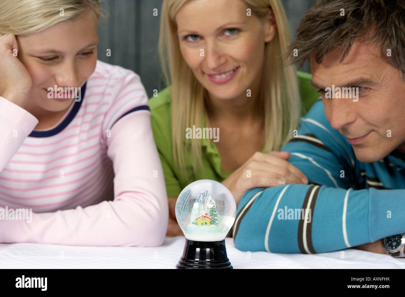 Mother, father and daughter looking at a snow dome, selective focus ...