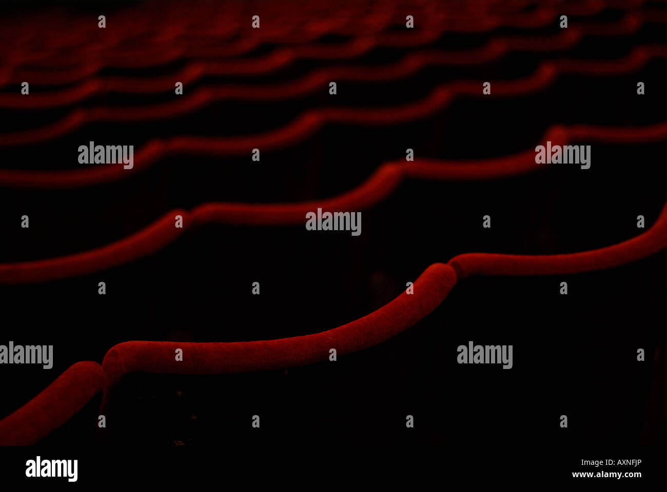 repeating pattern of red velvet seats in dimly lit theatre Stock Photo ...