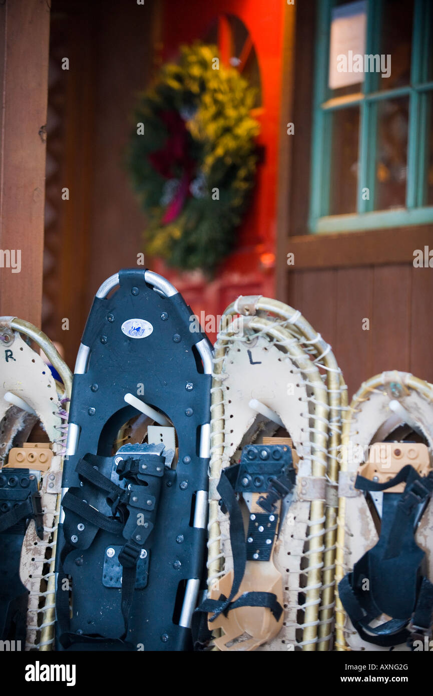 A HOLIDAY WREATH HANGS ON A DOOR WITH SNOWSHOES IN FOREGROUND ...