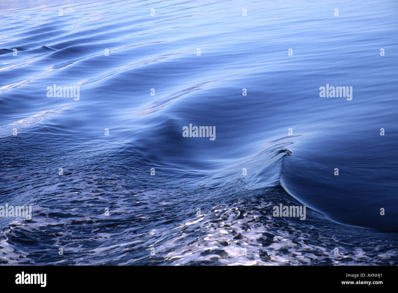Pattern formed by bow wave from boat on blue water Stock Photo - Alamy