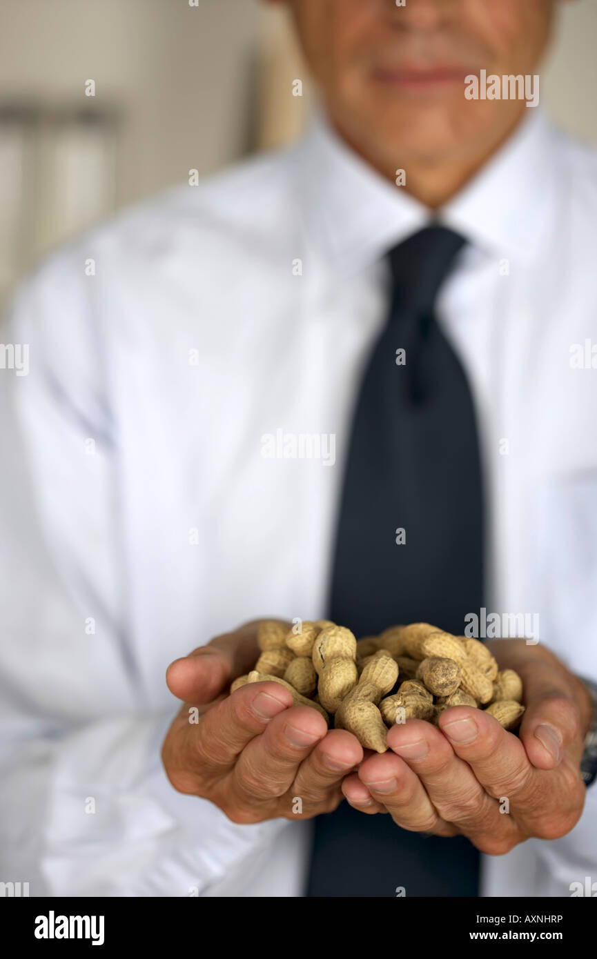 Businessman holding peanuts Stock Photo - Alamy