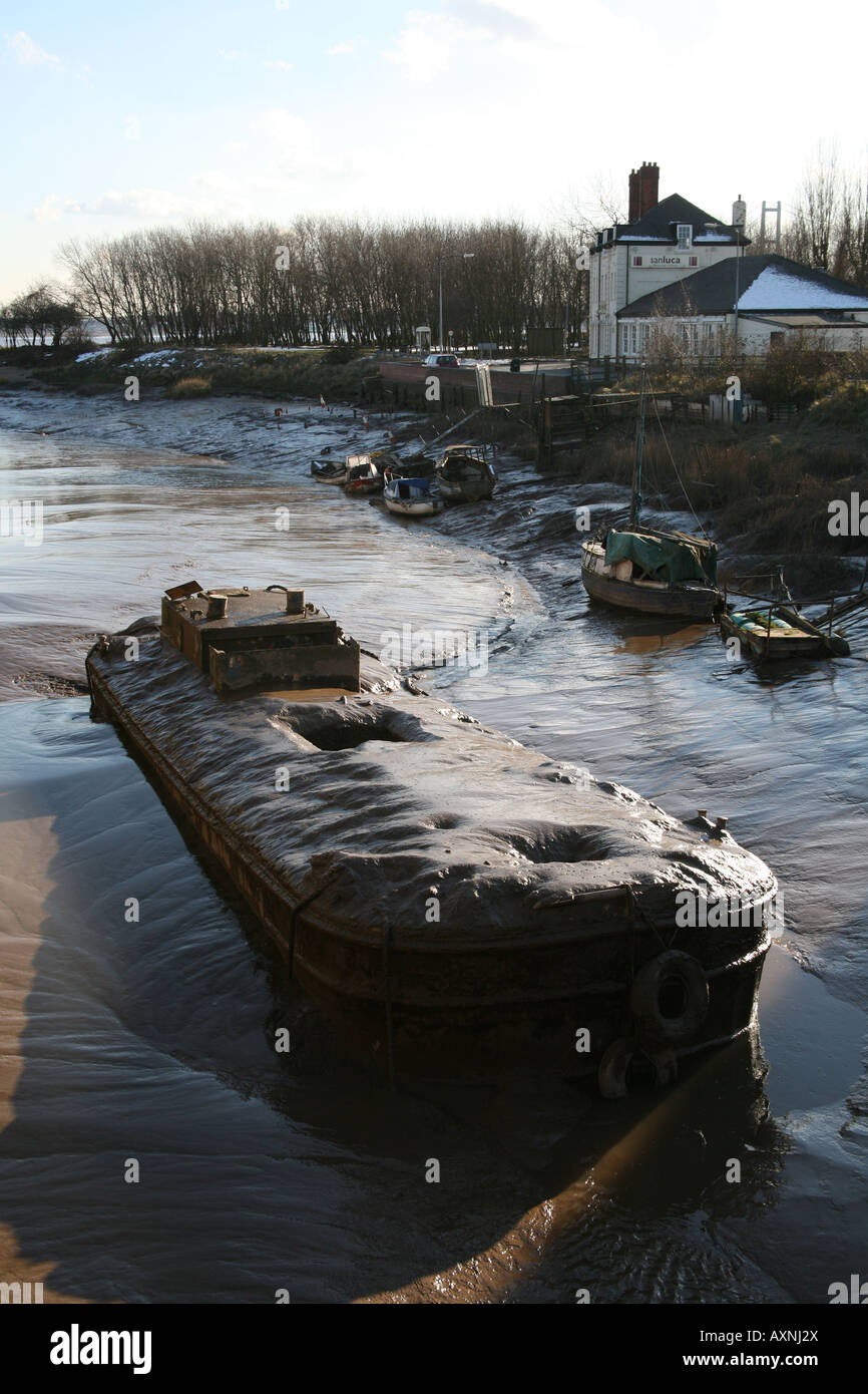 An old boat covered in silt and mud and stuck in the water Stock Photo ...