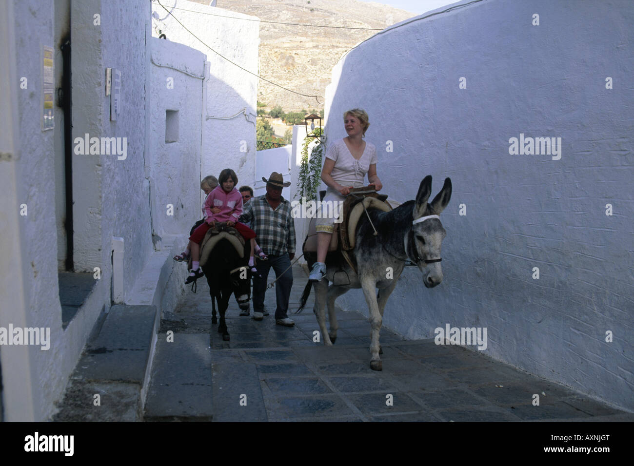 Narrow street of town White washed walls Two people riding donkeys ...