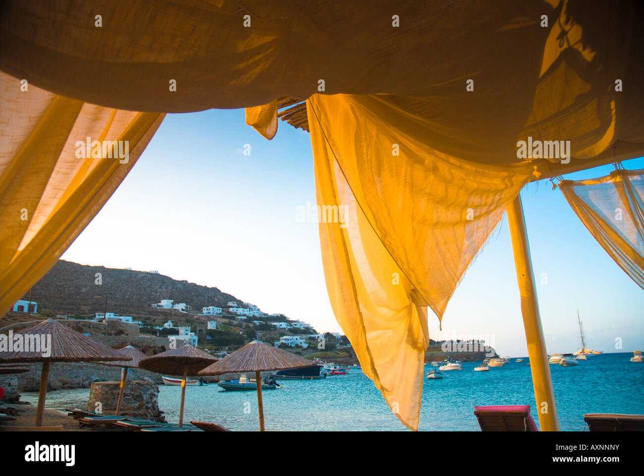 Ornos Beach, Mykonos, Greece. Relaxing under a sheer canopy at sunset ...
