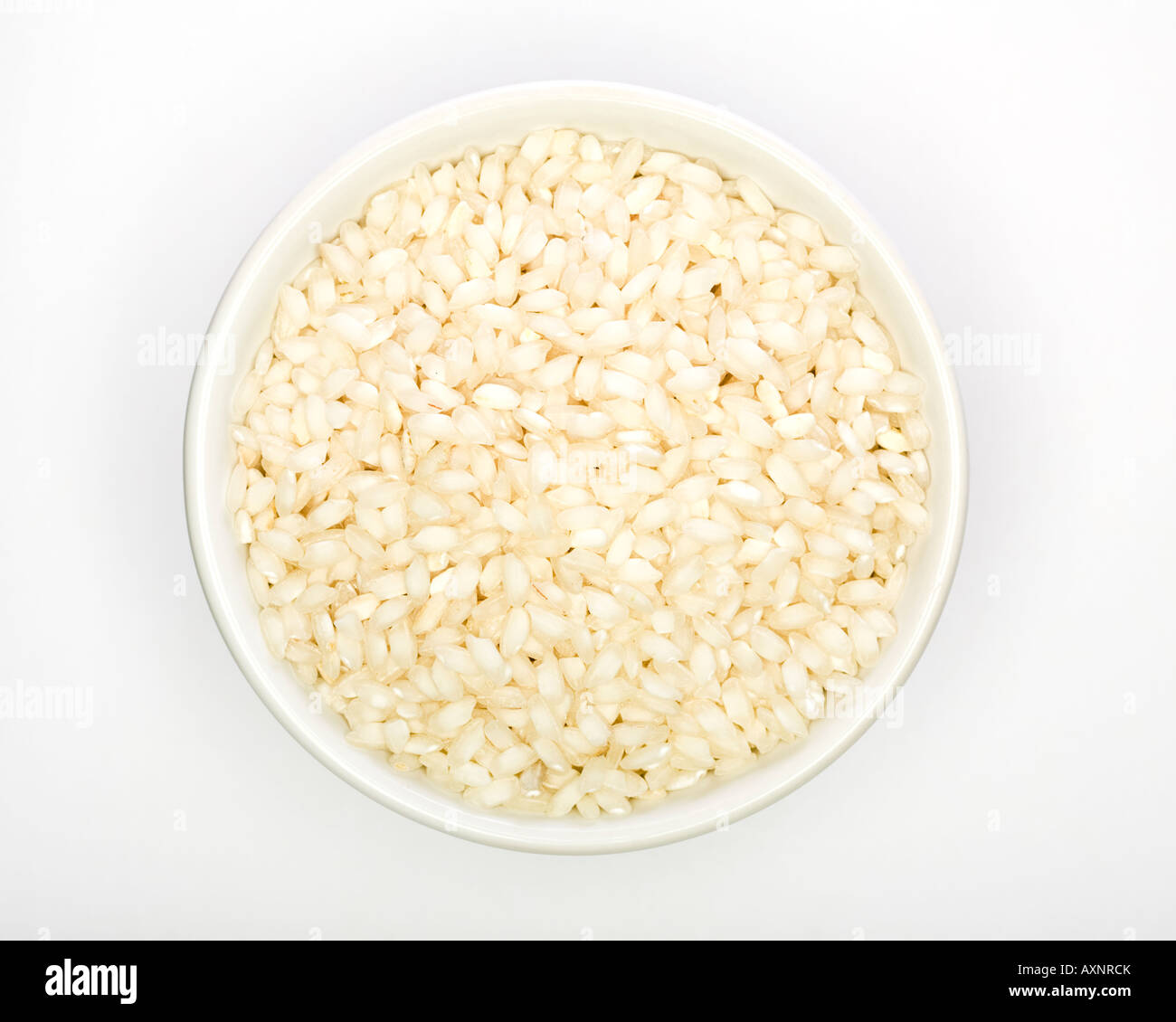 Organic Arborio rice in a white bowl on a white wooden background, top ...