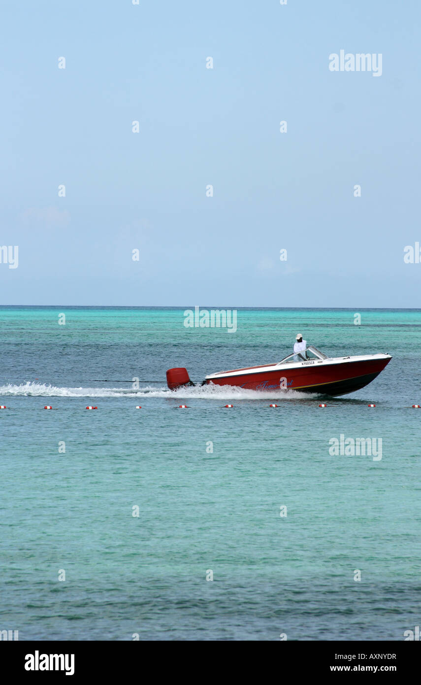 Bahamas beach red motor boat into the blue sea water with a sailer ...