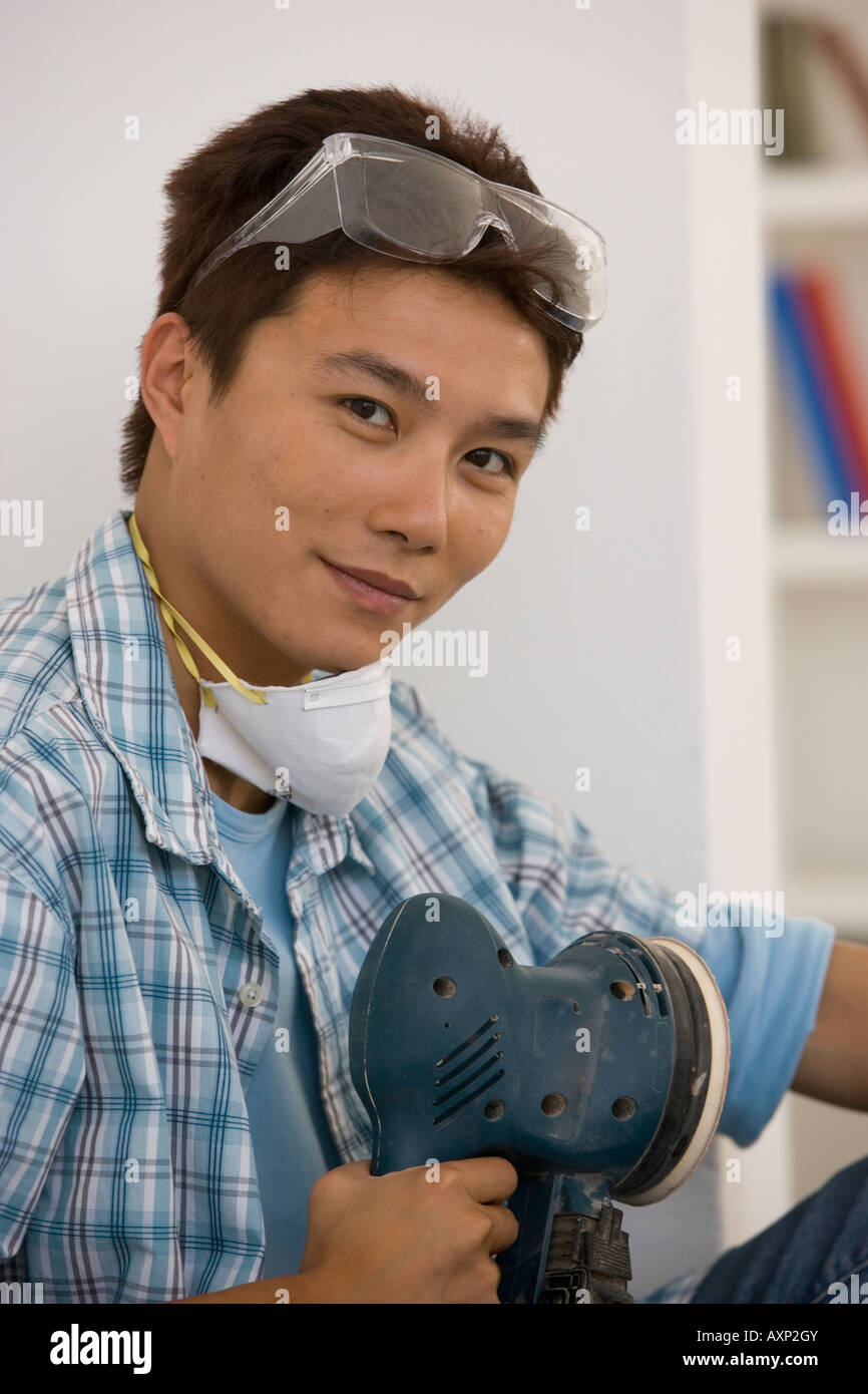 Asian man holding power sander Stock Photo - Alamy
