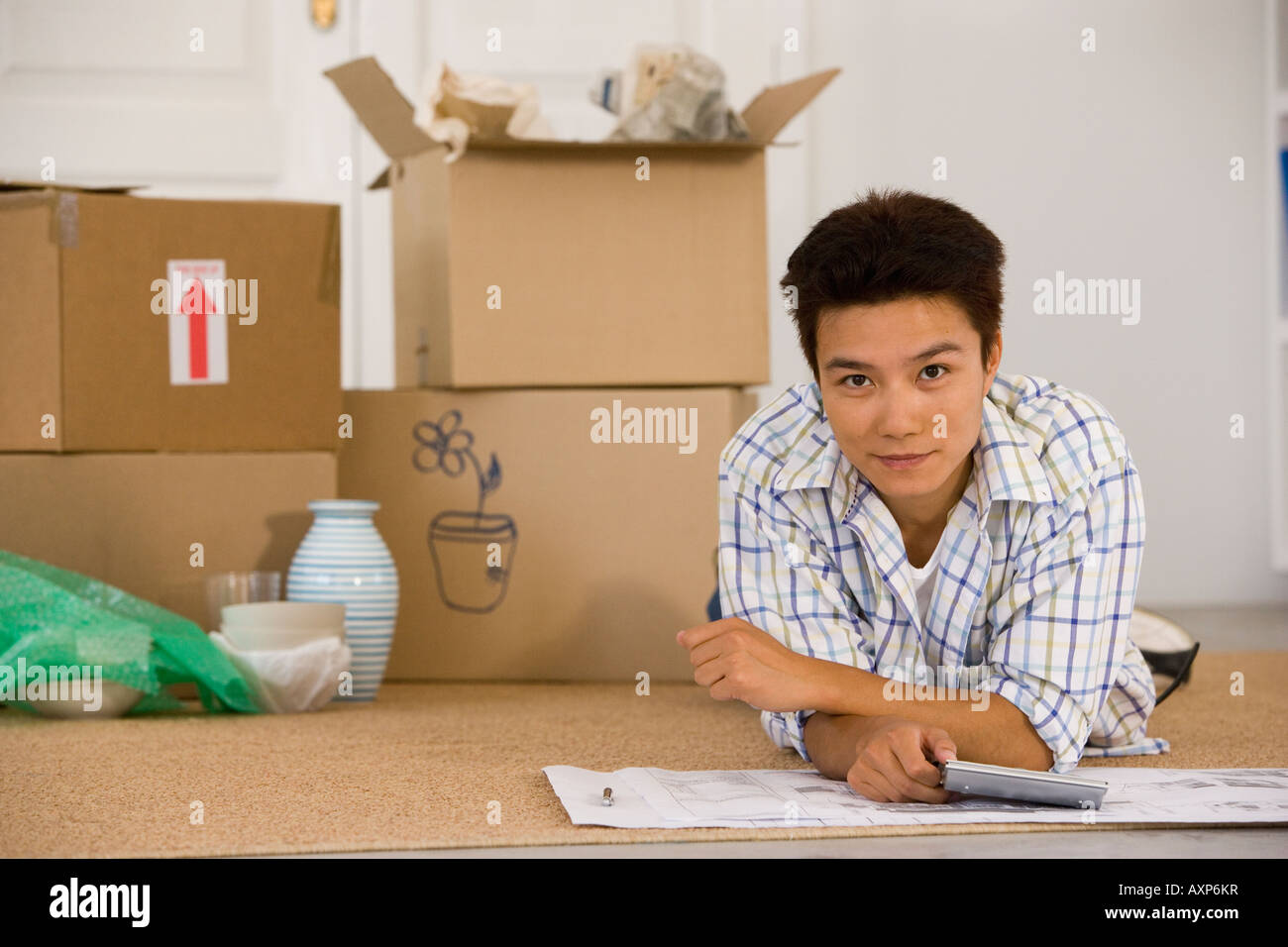 Asian man next to unpacked moving boxes Stock Photo - Alamy