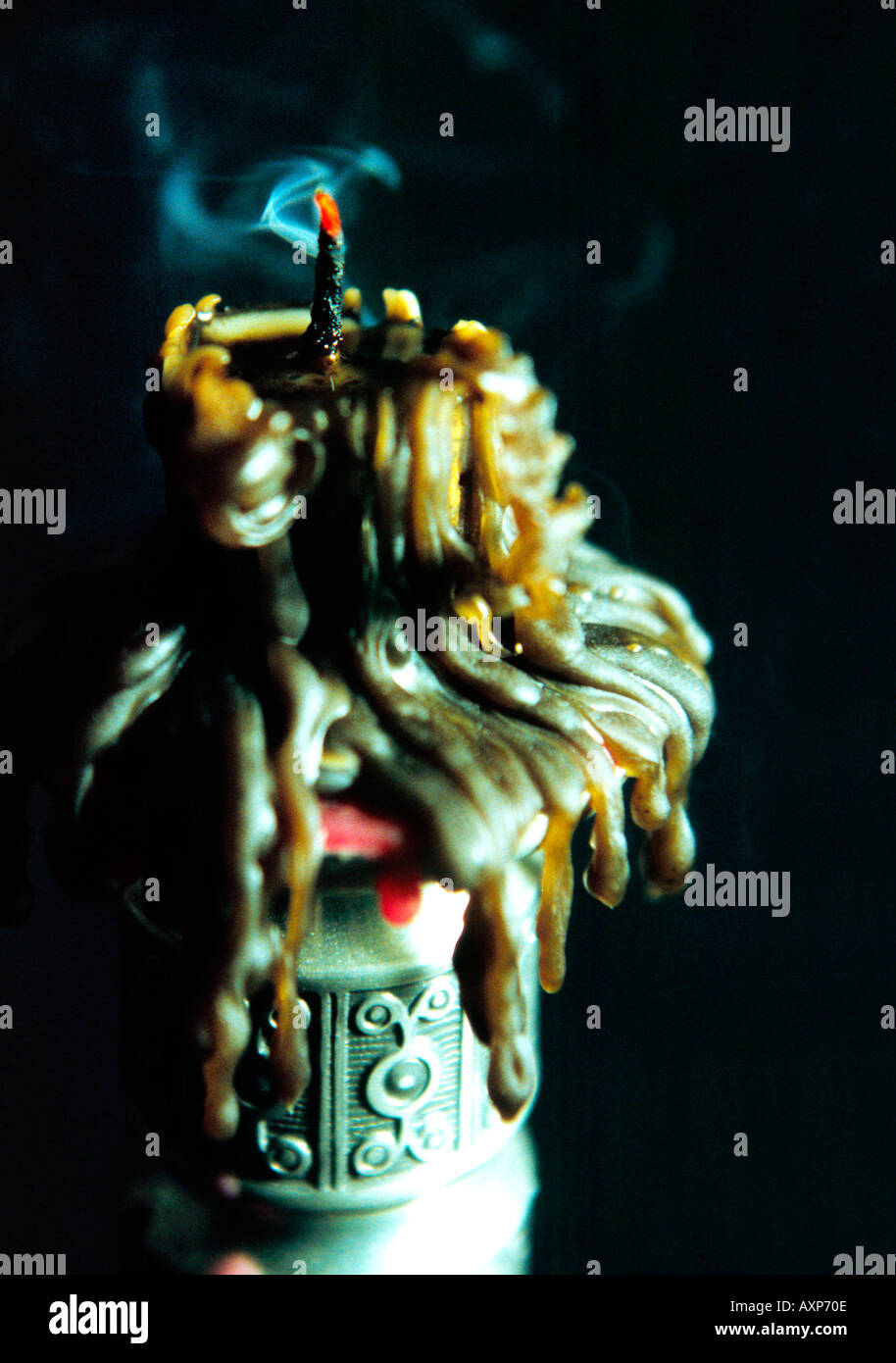 Close up of a smoldering smoking candle with trickles of melted wax ...
