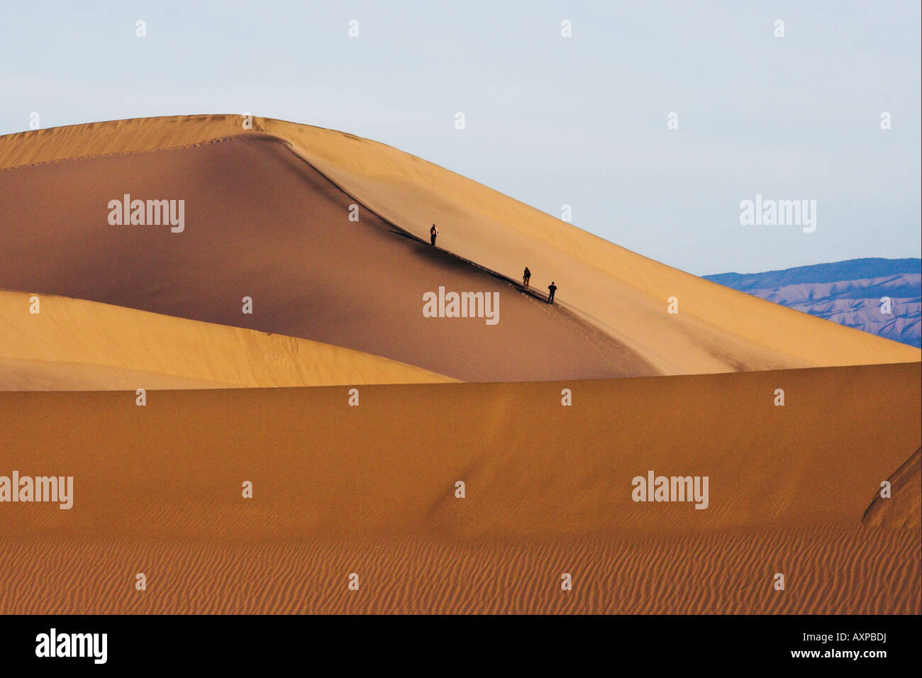 three people on sand dunes Stock Photo - Alamy