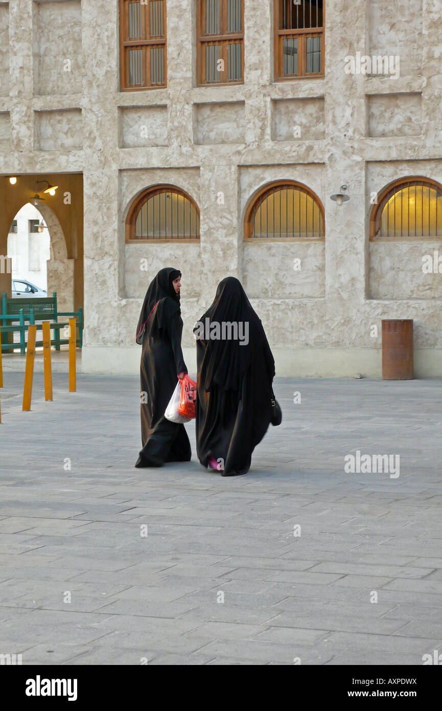Two local Qatari women in local dress walk outside a mosque in Souq ...