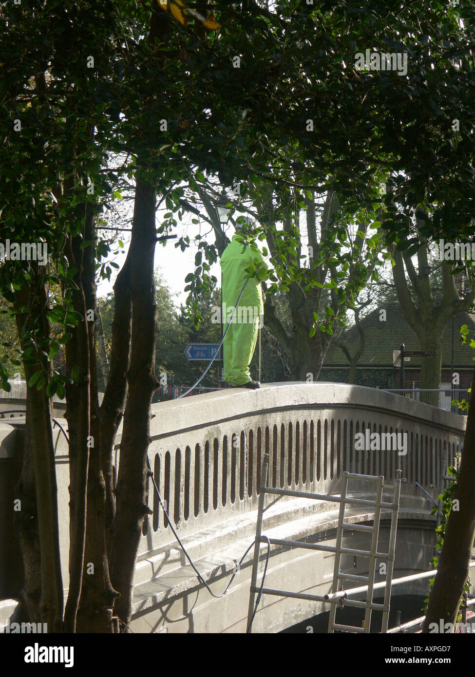A workman cleans an old precast concrete bridge with a high pressure ...